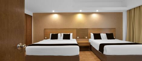 Quarto de hotel com duas camas, cabeceiras de madeira e chão de madeira.