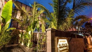 Uma entrada com tema tropical e uma placa com a inscrição 'Nhà Nhieu Doi Tropical Home'.