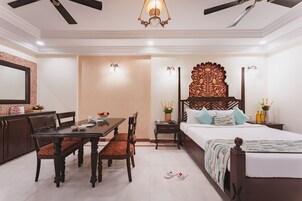 Quarto de hotel com cama, mesa de cabeceira, e área de refeições com mesa e cadeiras.