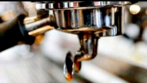 Máquina de café expresso a servir um café numa chávena com o logótipo 'illy'.