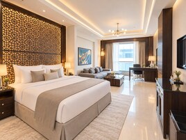 Quarto de hotel moderno com uma cama grande, um sofá, uma escrivaninha e uma televis ão.