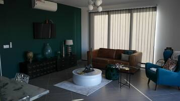 Uma sala de estar moderna com um sofá marrom, uma poltrona azul, uma mesa de centro redonda e uma TV fixada na parede.