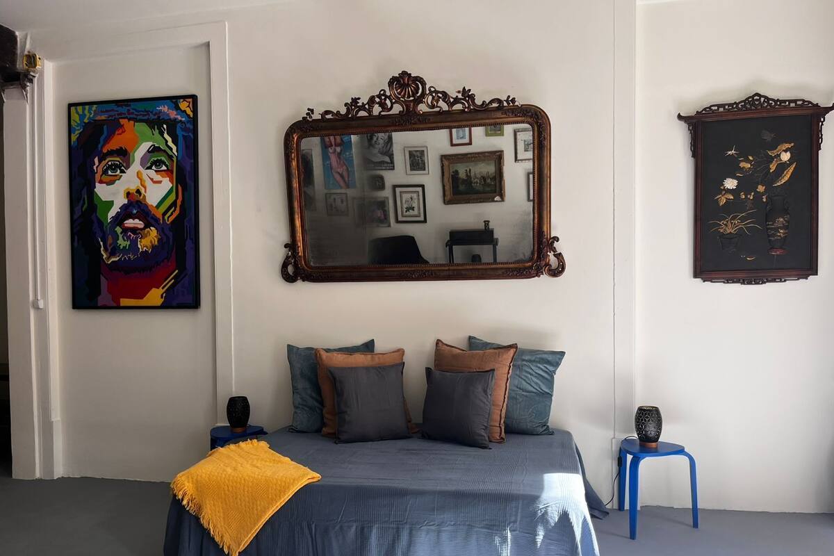 Quarto com uma cama grande, um espelho e obras de arte nas paredes.