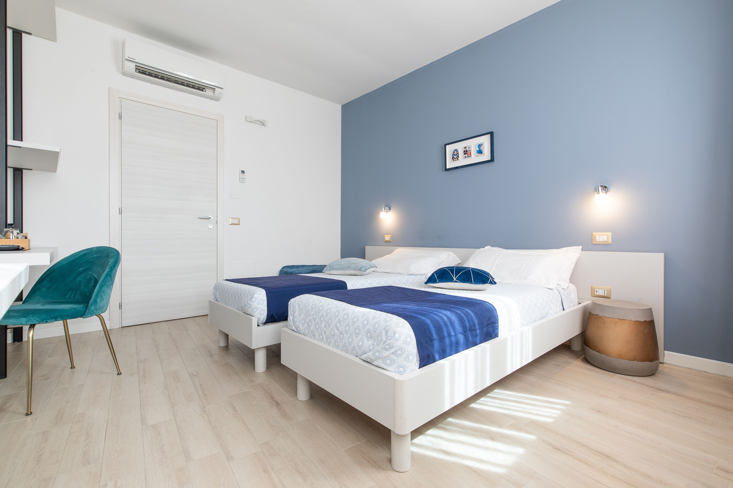 Quarto com duas camas, uma escrivaninha e uma cadeira.