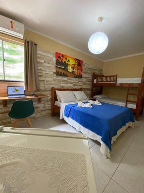 Quarto com uma cama beliche, uma escrivaninha com um laptop, uma cadeira e um quadro na parede.