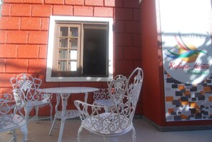 Edifício de tijolos vermelhos com janela emoldurada por branco e placa indicando Refijo Hostel Fortaleza.