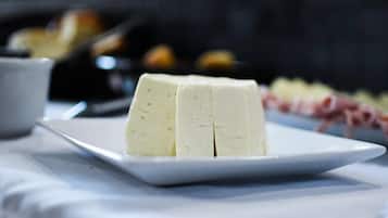 Um prato branco com uma fatia triangular de queijo sobre uma toalha de mesa.