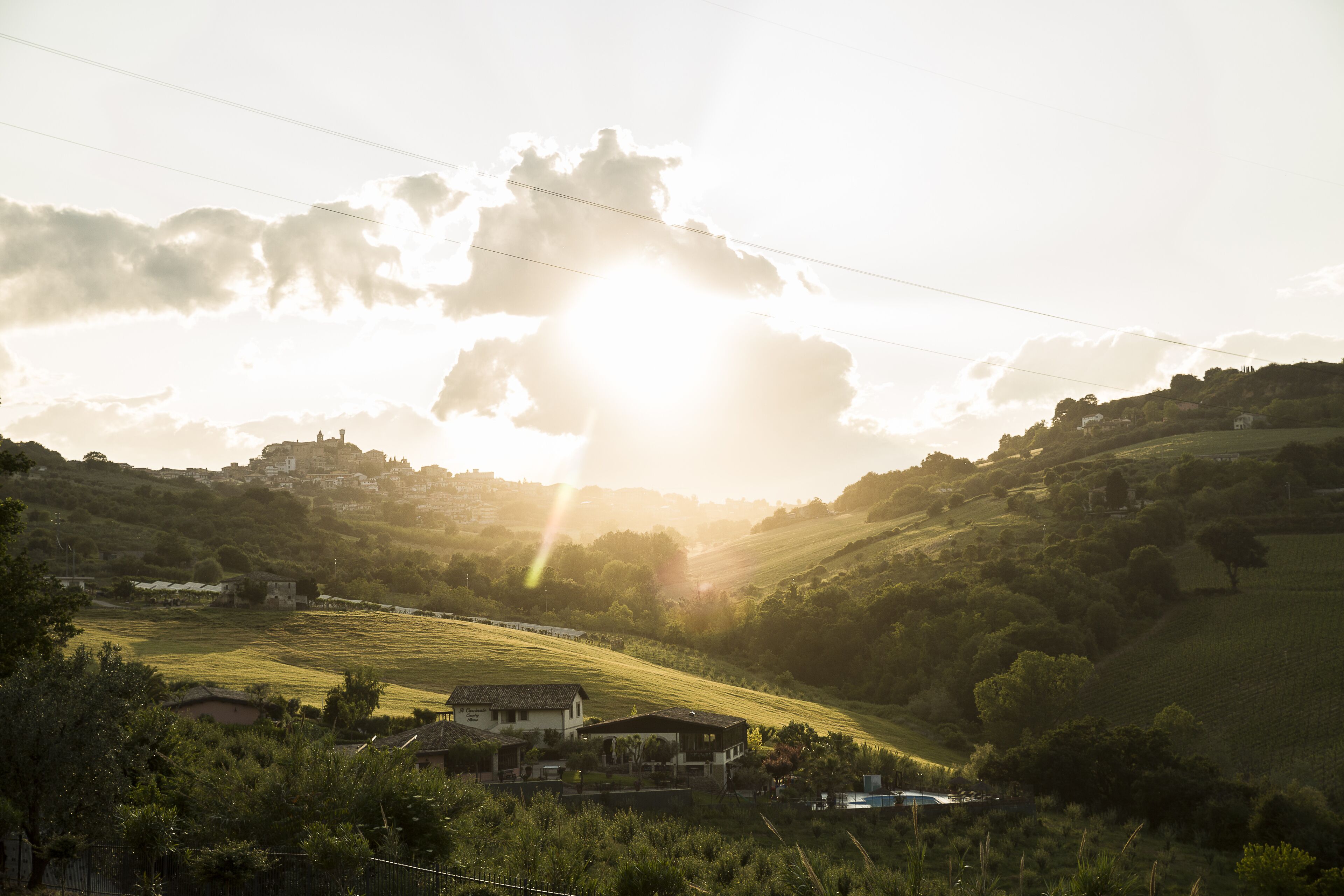 Paisagem rural com colinas ondulantes, algumas casas e céu limpo.