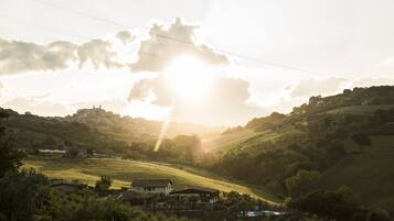 Paisagem rural com colinas ondulantes, algumas casas e céu limpo.