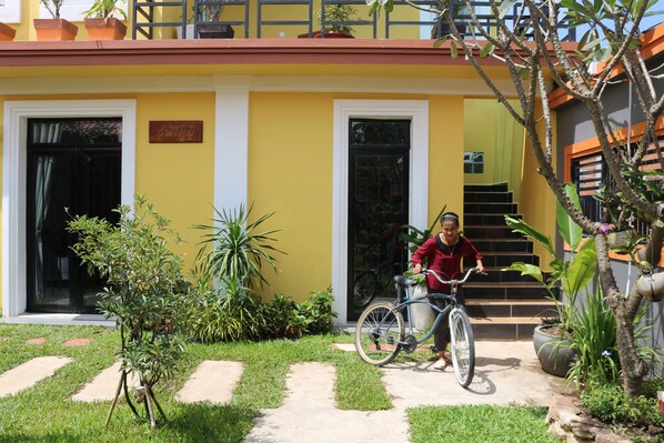 Um edifício amarelo com uma escadaria que leva a uma porta. Uma bicicleta está estacionada em frente ao prédio.