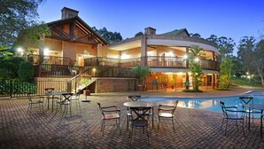 Um edifício de dois andares com piscina, área de estar ao ar livre e escadaria que dá acesso ao andar superior.
