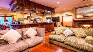 Uma área de bar com balcão, banquetas e um espaço de estar com sofás e lareira.
