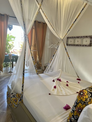 Quarto com cama sob um dossel, um cabideiro na parede e vista para o exterior.