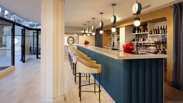 Uma área de bar moderna com balcão, banquetas e luminárias pendentes.