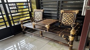 Conjunto de móveis de bambu tradicional com encostos e apoios de braço trançados, sobre um chão de azulejos.
