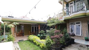 Uma casa de dois andares com varanda, plantas em vasos e um pequeno jardim.