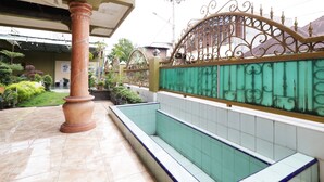 Um pátio com piscina, um portão decorativo e uma parede revestida de azulejos.
