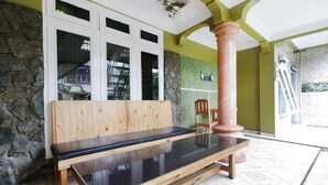 Um banco de madeira com almofada preta em um quarto com paredes de pedra, uma parede verde e um grande pilar.