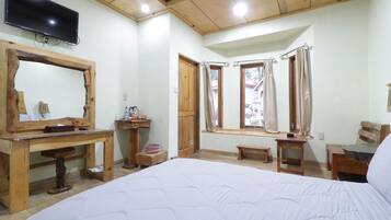 Um quarto com uma cama grande, móveis de madeira, uma televisão e uma janela com cortinas.