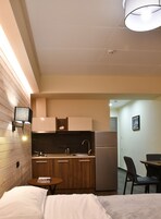 Quarto de hotel compacto com cozinha compacta, uma cama, uma pequena mesa e uma cadeira.
