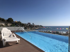 Piscina com vista para o mar e um deck com espreguiçadeiras.