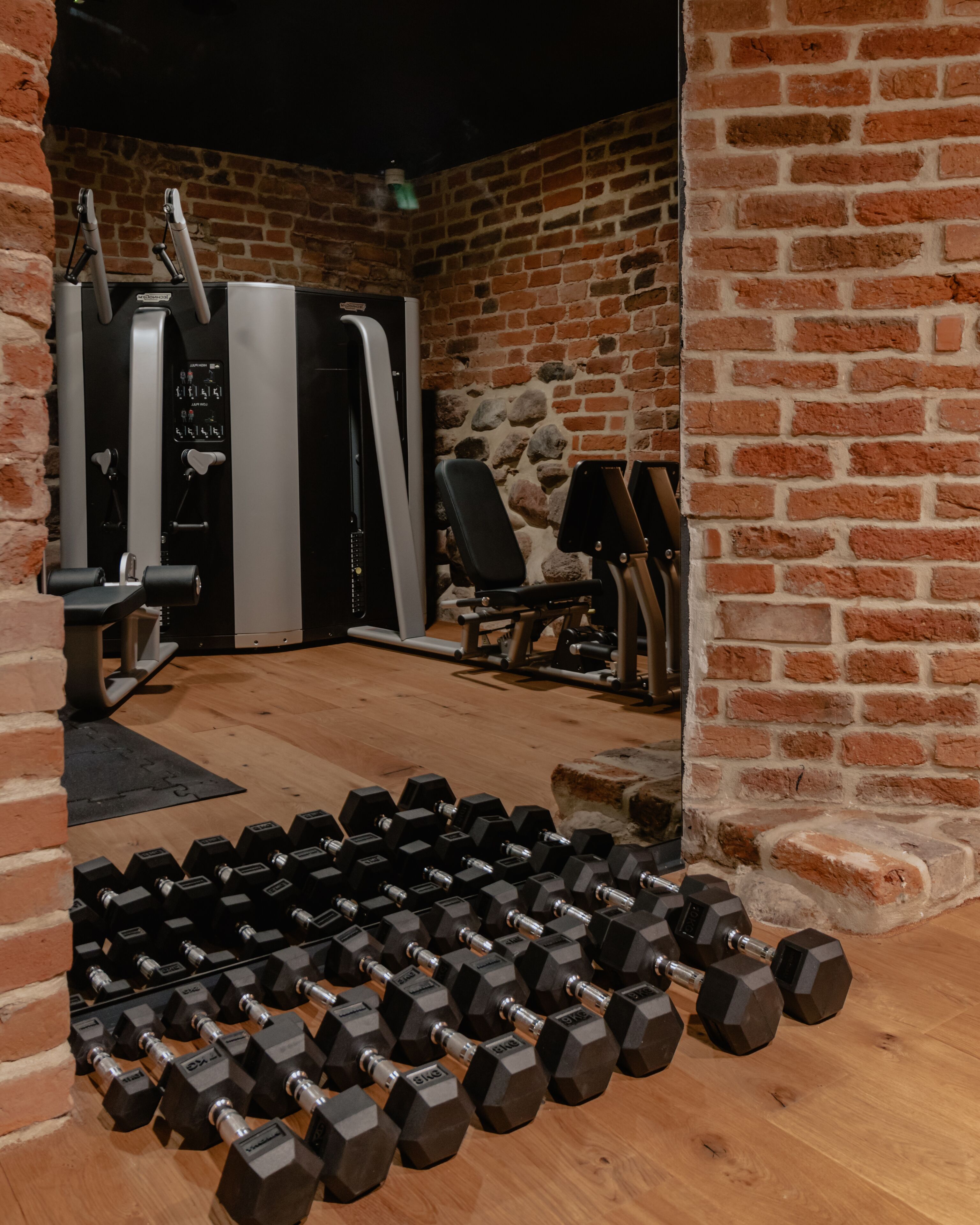 Uma academia com equipamentos de ginástica, incluindo halteres e um banco.