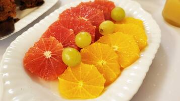 Um prato branco com fatias de laranja e toranja, e uvas verdes.