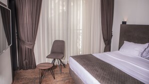 Quarto de hotel com uma cama, uma cadeira e uma televisão.