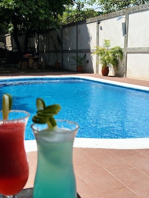 Piscina com duas bebidas em primeiro plano.