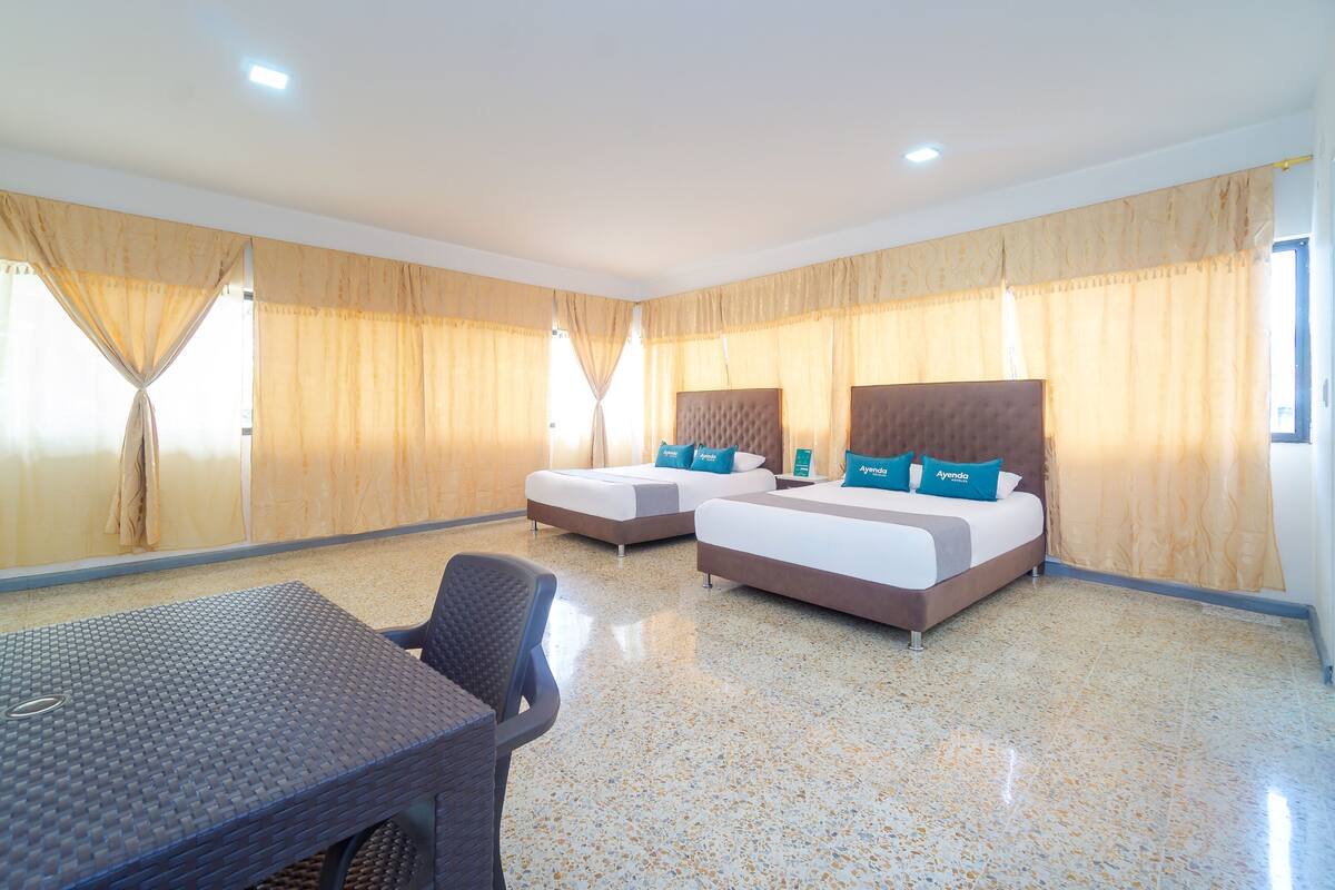 Quarto de hotel com duas camas, uma mesa de jantar e uma cadeira.