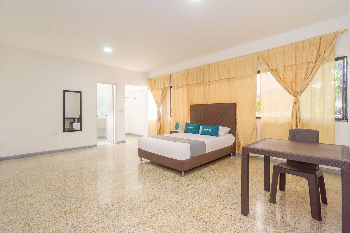 Quarto de hotel com uma cama, uma mesa e uma cadeira.