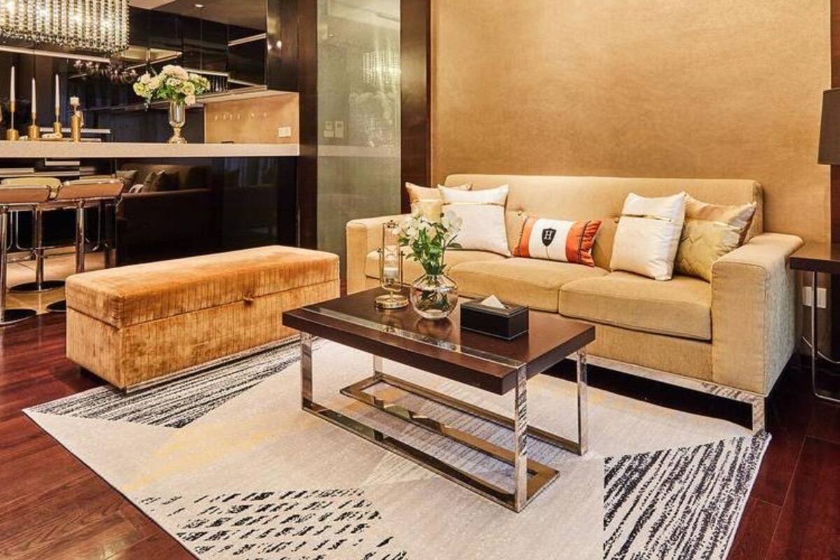 Uma sala de estar moderna com sofá, banqueta e mesa de centro.
