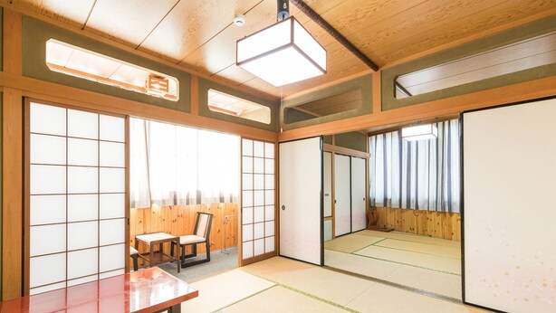 Um quarto japonês tradicional com tatames, uma mesa de madeira baixa, portas deslizantes e um espelho grande.