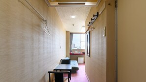 Um corredor estreito com cozinha compacta, uma cama e janela com vista para a cidade.