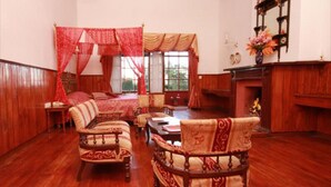 Quarto tradicional com cama, lareira e área de refeições com cadeiras e mesa.
