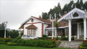 Um edifício tradicional com telhado telhado, varanda coberta e um carro estacionado em frente.