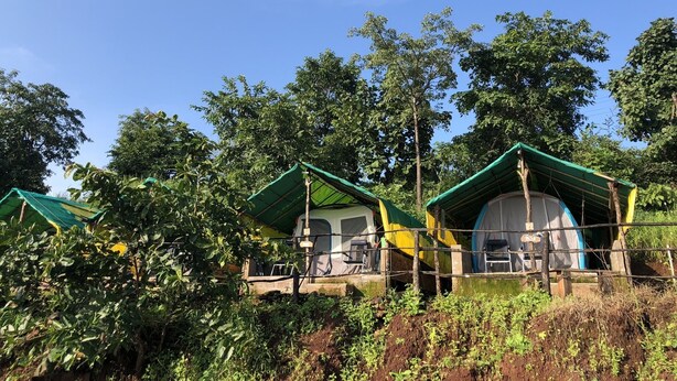 Fileira de cabanas simples com telhados verdes, rodeadas por vegetação densa.