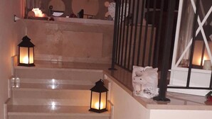 Uma escadaria com três lanternas iluminadas, um corrimão branco e uma parede com padrões circulares.