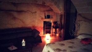 Um quarto aconchegante com parede de pedra, lareira, sofá e cama.