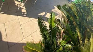 Um pátio externo com mesa e cadeiras, uma porta e uma parede com um círculo amarelo e texto.