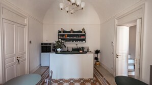 Cozinha com ilha central, armários brancos, lustre e piso estampado.