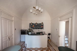 Cozinha com ilha central, armários brancos, lustre e piso estampado.