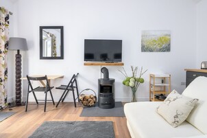 Uma sala de estar moderna com um sofá, uma TV, uma lareira e um espaço de jantar com cadeiras.