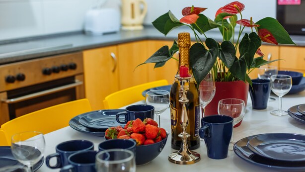 Mesa posta com pratos azuis, taças de vinho e uma tigela de morangos.