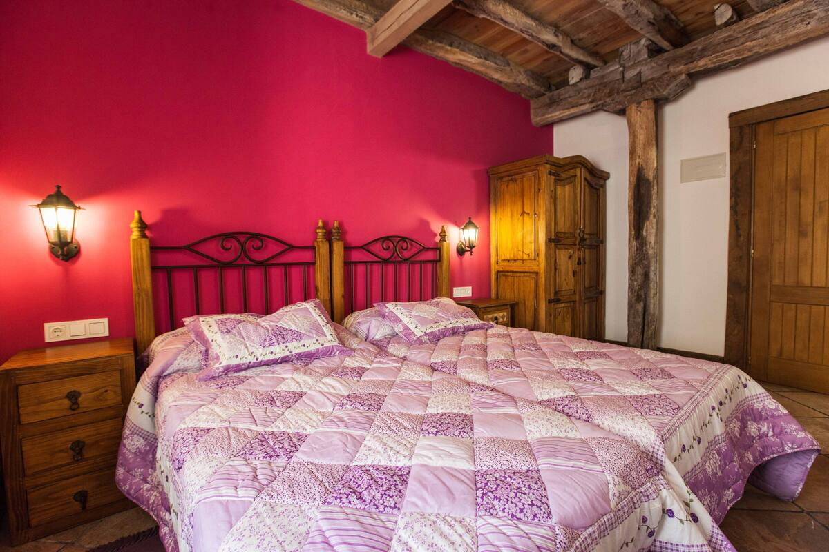 Quarto com uma cama grande, cabeceira de madeira, duas mesinhas de cabeceira e um guarda-roupa.