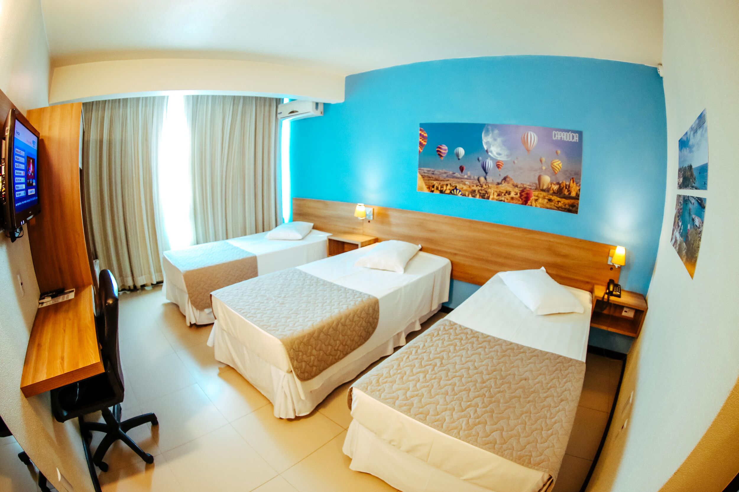 Quarto de hotel com duas camas, uma escrivaninha e uma televisão.