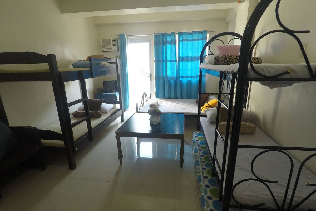 Quarto de dormitório com beliches, uma mesinha e uma televisão.