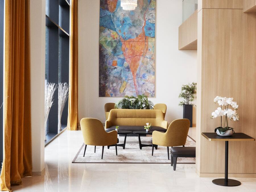 Um lobby moderno com uma grande pintura abstrata, um candelabro e uma área de estar com uma mesa de centro.