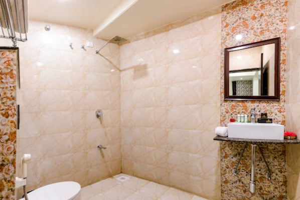 Uma casa de banho com chuveiro, sanita e lavatório.