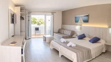 Quarto de hotel com uma cama, escrivaninha, cadeira, mesa pequena e porta de vidro deslizante que dá para uma área externa.